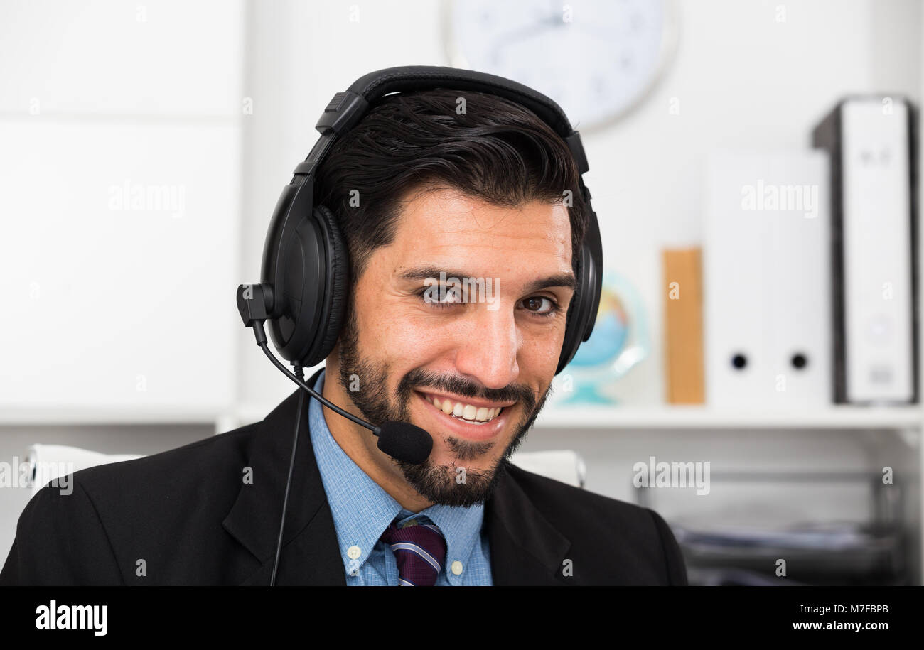 Portrait of spanish man dispatcher who is talking with client in office ...