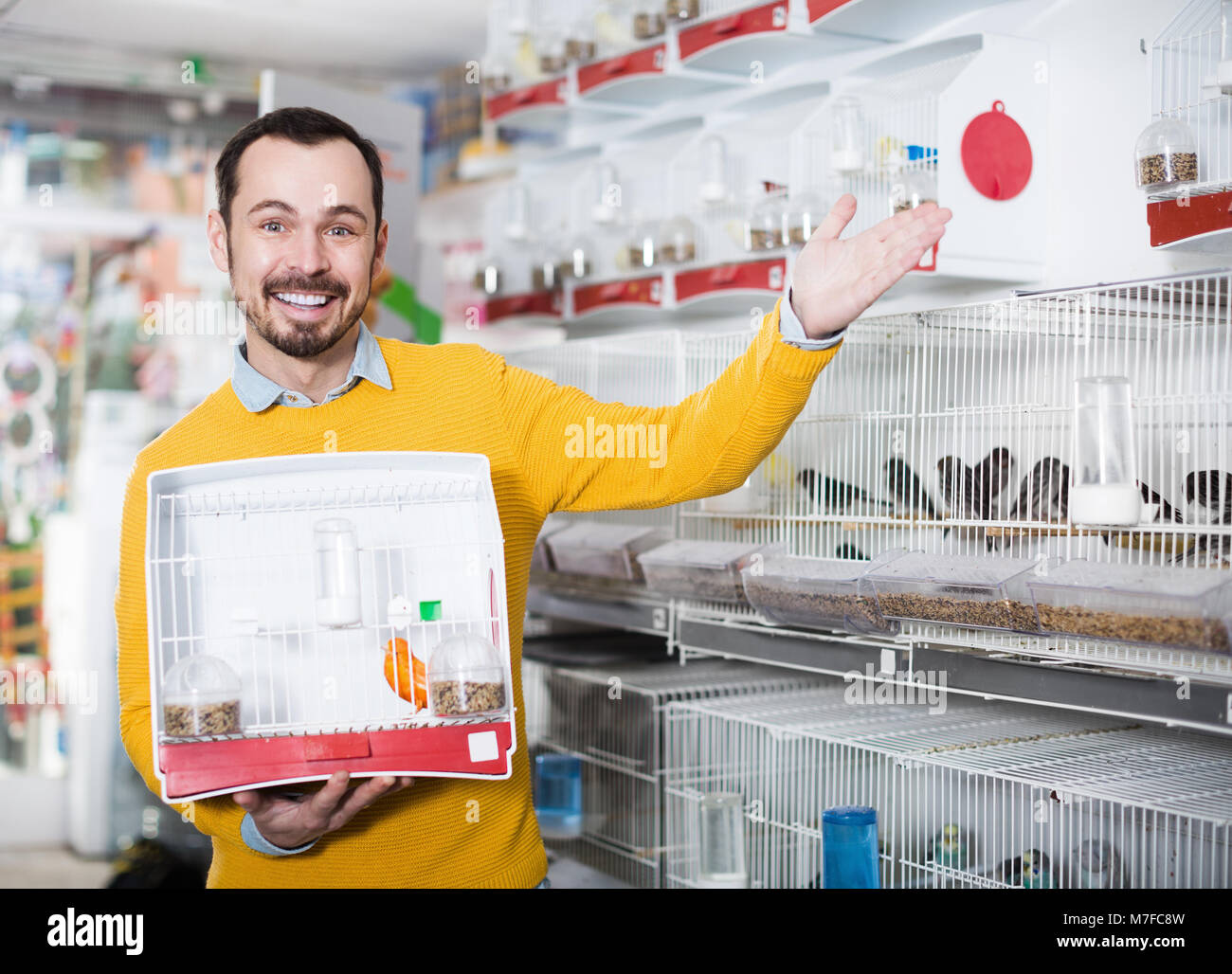 Young happy guy enjoying his purchase of canary bird in pet store Stock ...