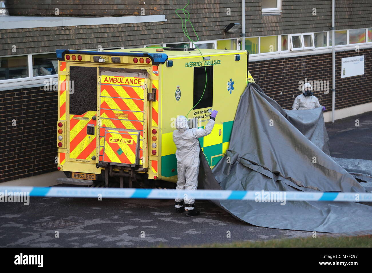 Military personnel in gas masks prepare to remove a second ambulance ...