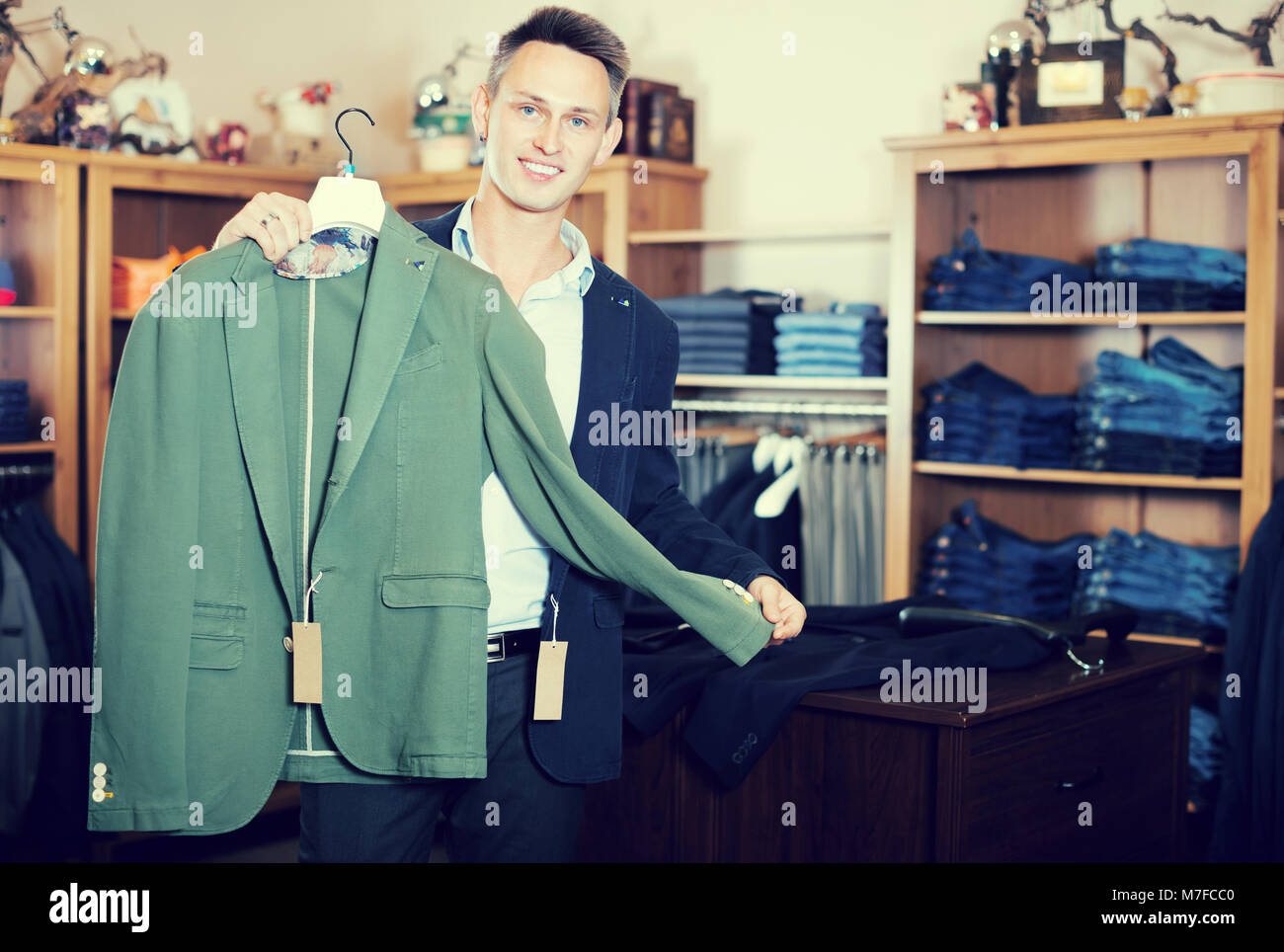 Smiling male customer choosing new jacket in man clothes store Stock ...