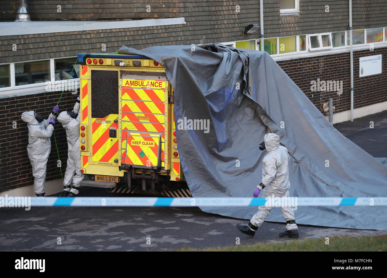 Military personnel in gas masks prepare to remove a second ambulance ...