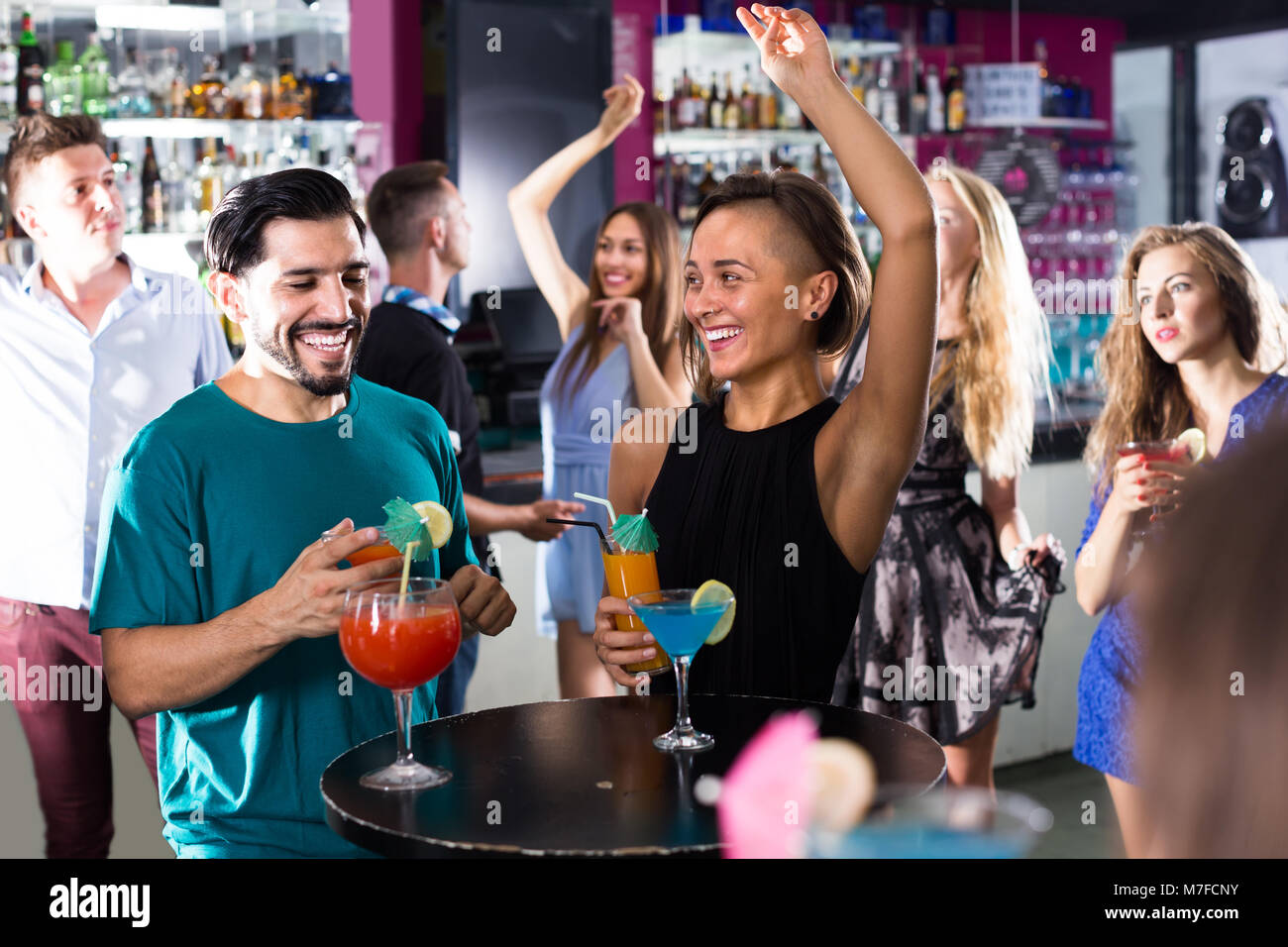 active male with female are talking and drinking cocktails on the party ...