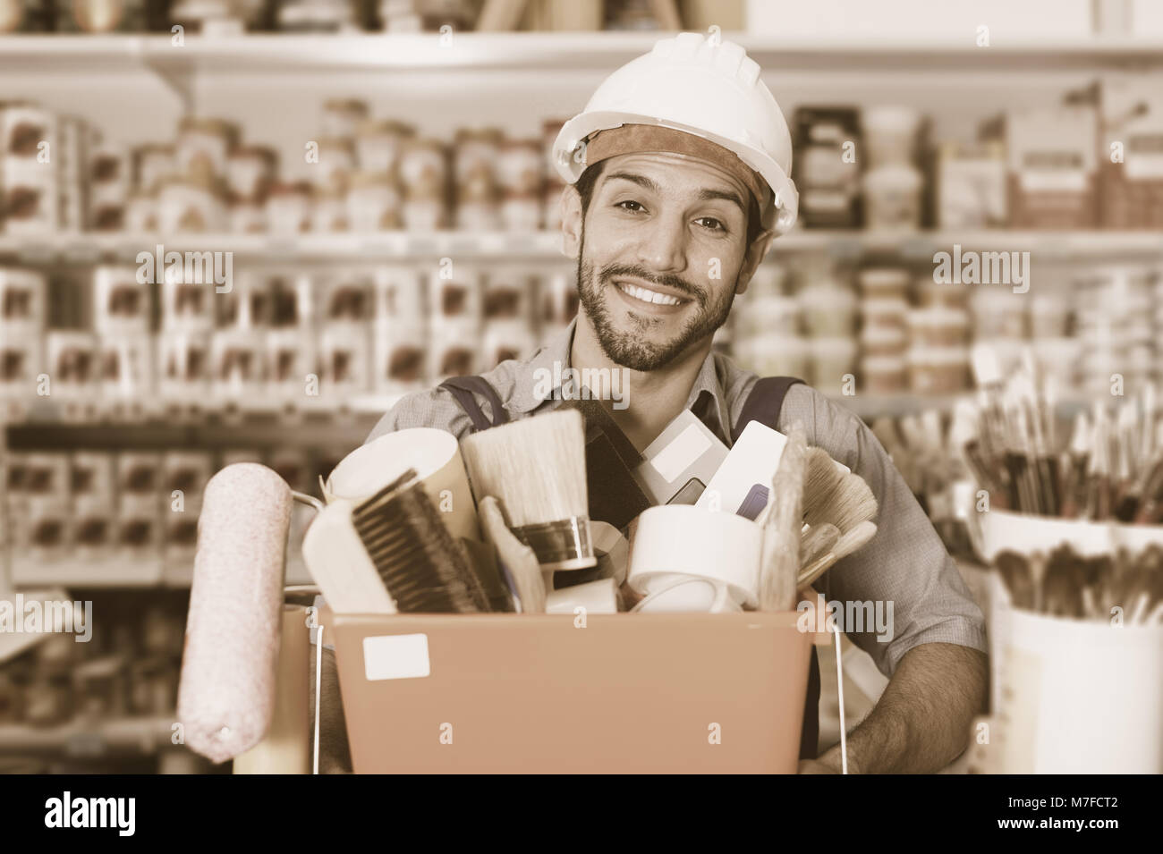 Smiling workman with tools in hands with purchases in paint shop Stock ...