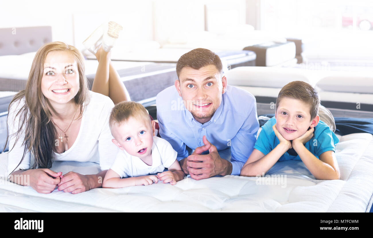 happy english parents with two young sons testing mattress in store ...