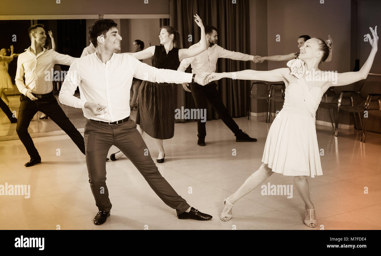 Young smiling people practicing vigorous jive movements in dance class ...