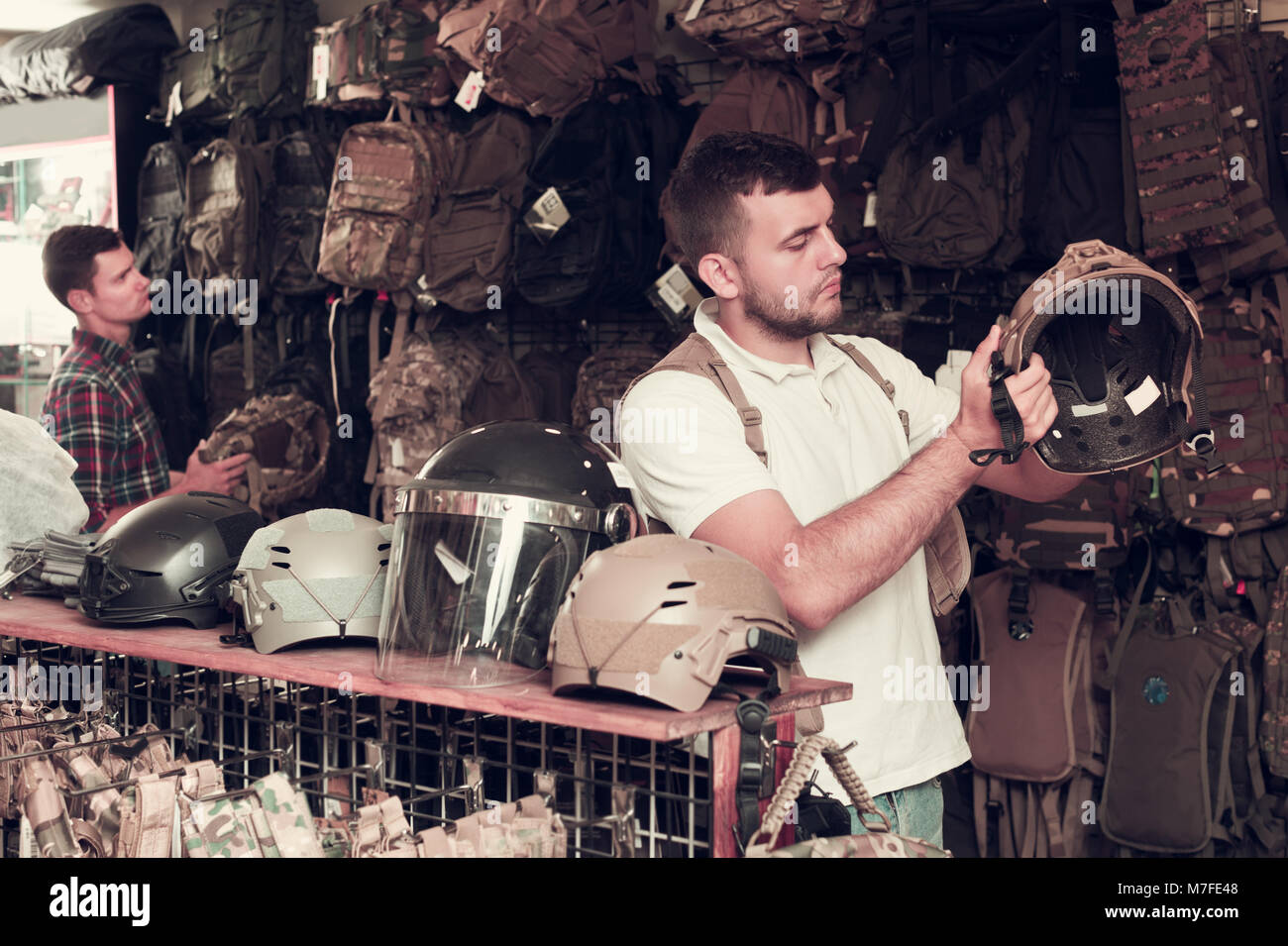 Adult serious men choosing helmet in army shop Stock Photo - Alamy