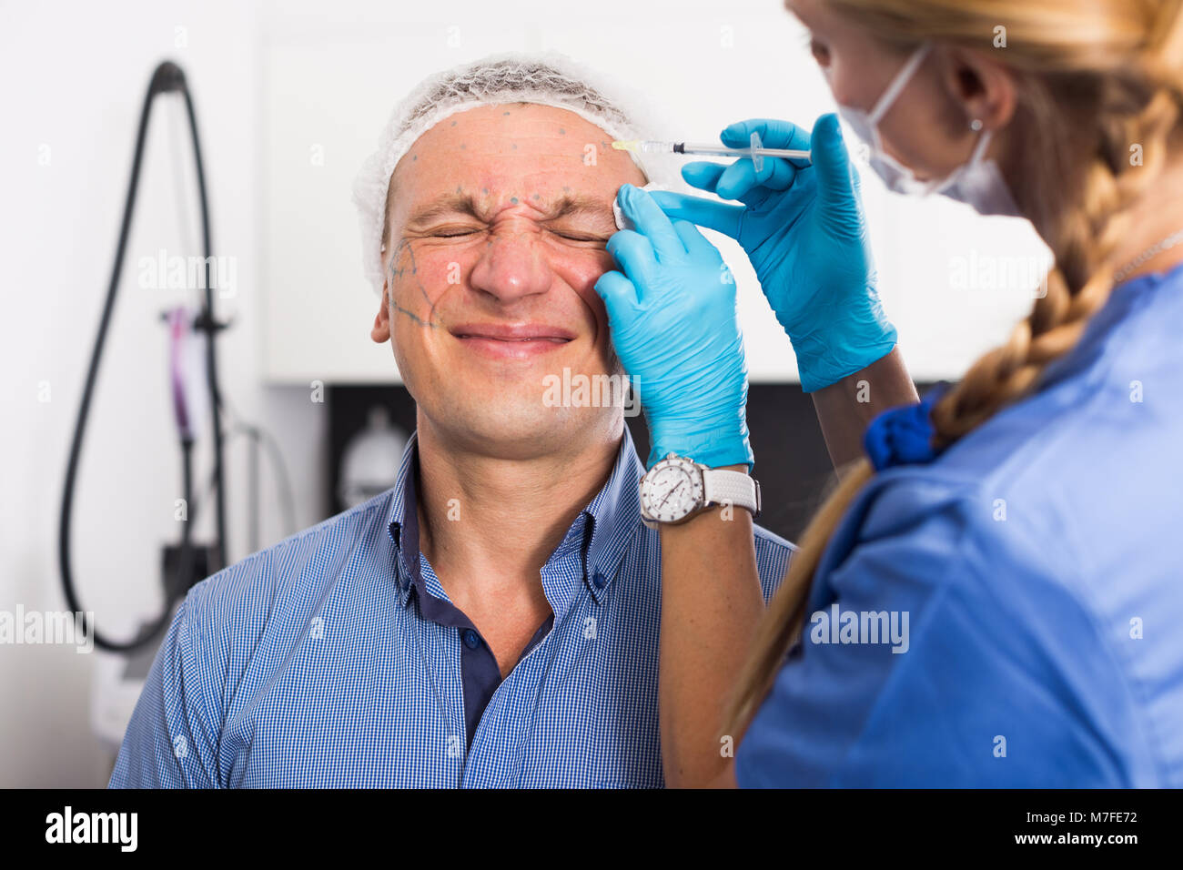 Female doctor is doing injection to patient in skin of face in estetic ...