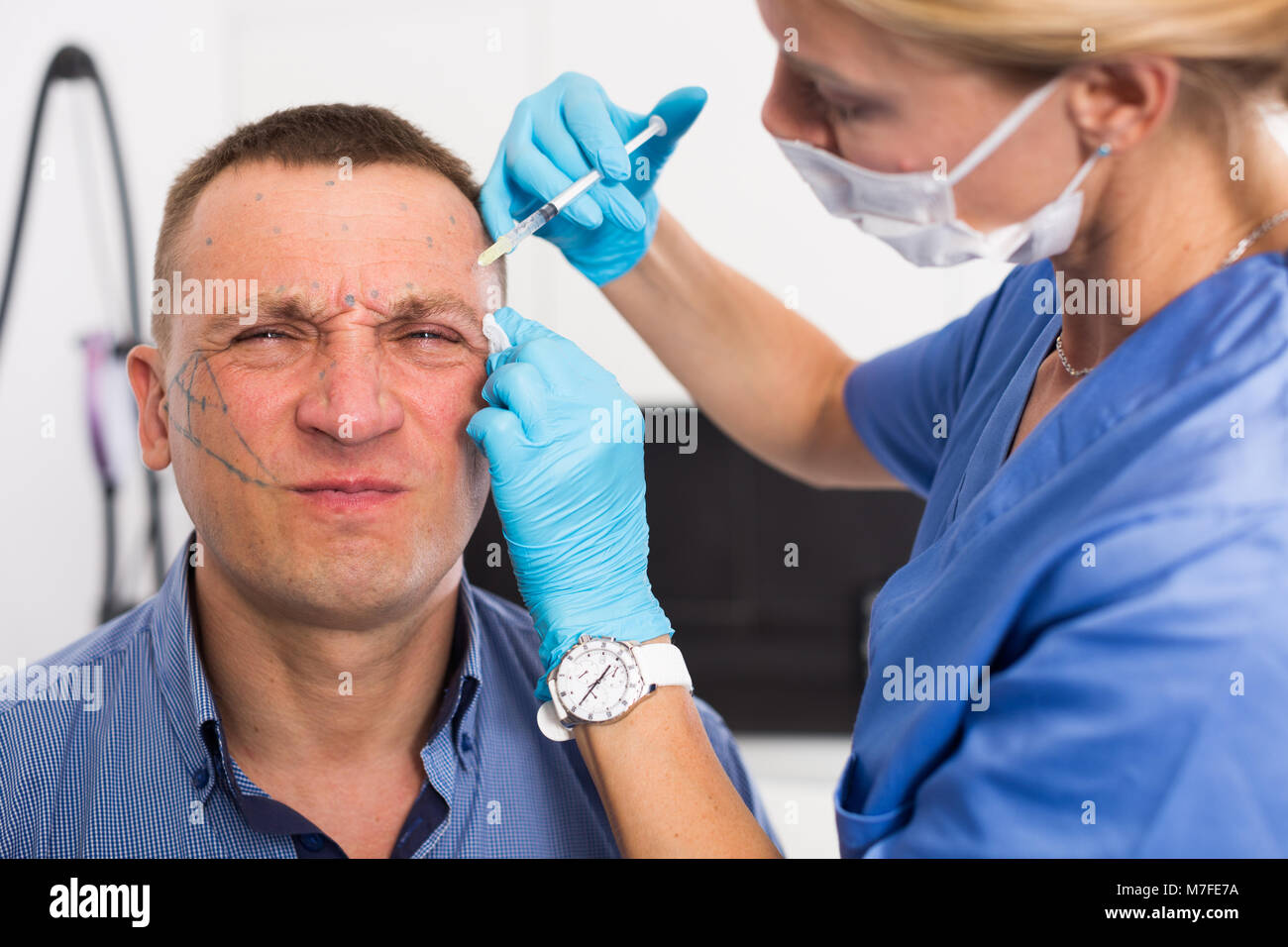 Female doctor is doing injection to patient in skin of face in estetic ...