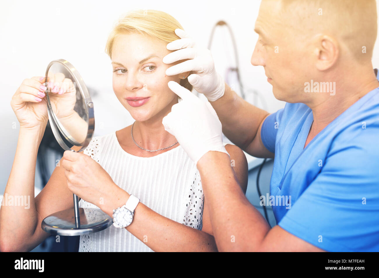 Doctor is examining woman patient behind mirror before the procedure in ...