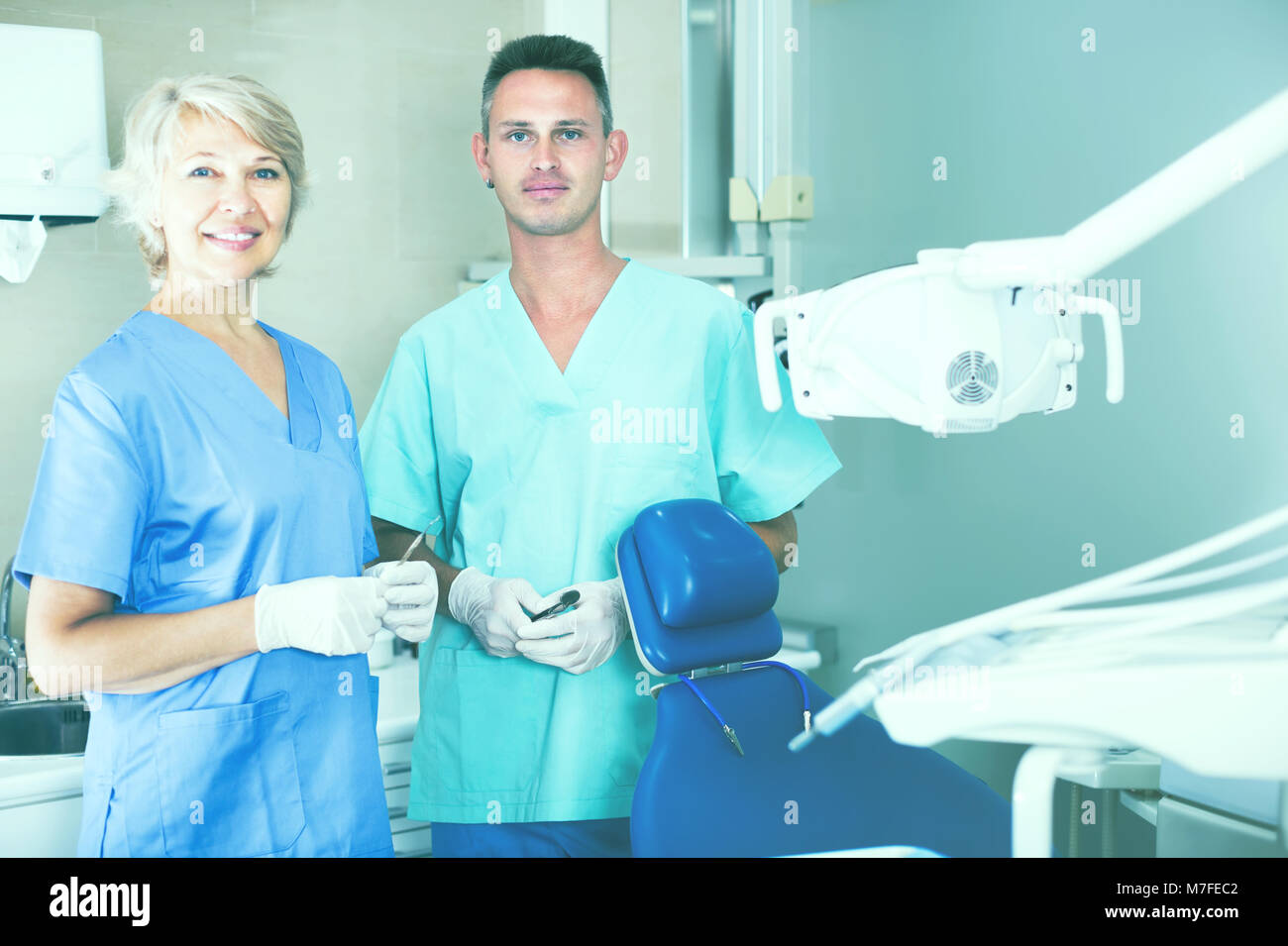 Portrait of professional smiling dentists standing in modern medical ...