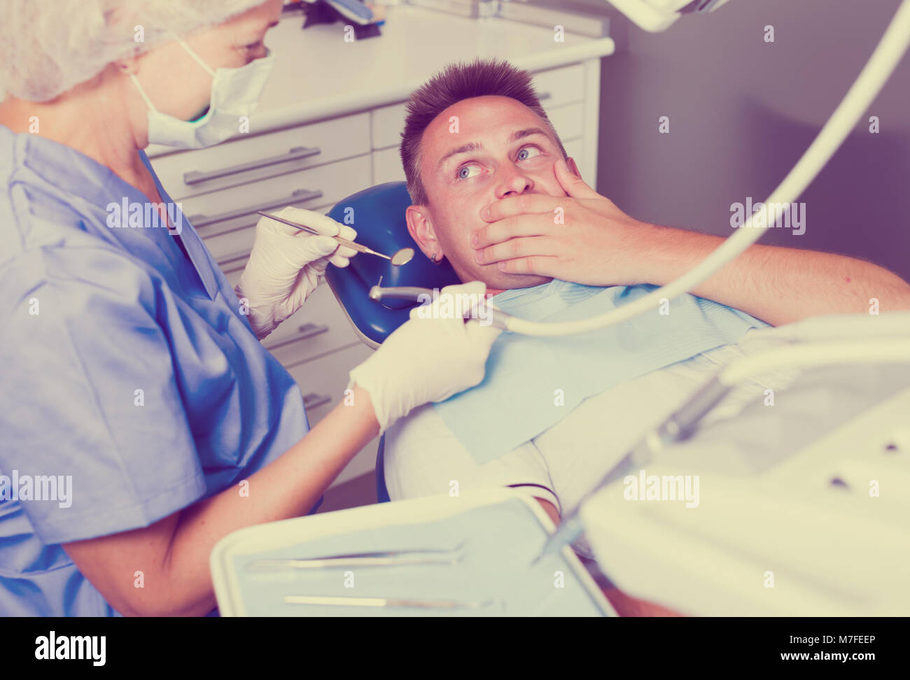 Frightened guy in dental chair not wanting to open his mouth afraid of ...
