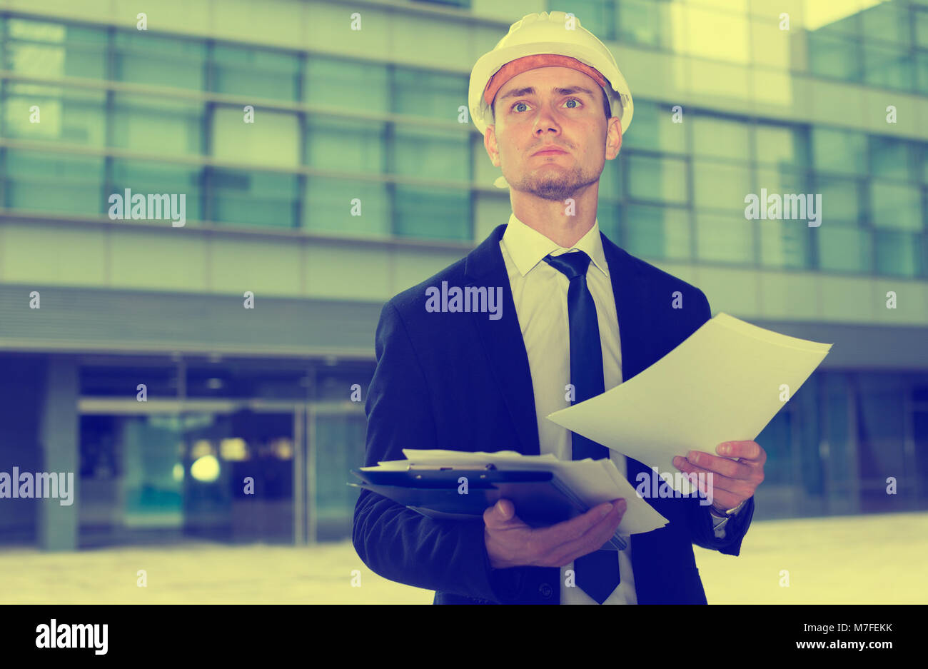 Engineer in suit and hat with folder is looking into documents with ...