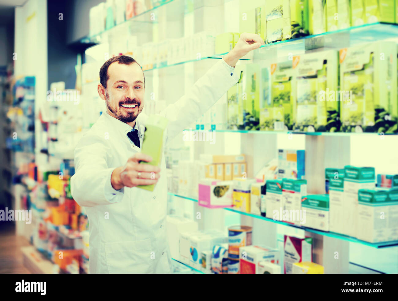 Smiling man pharmacist showing right drug in drugstore Stock Photo - Alamy