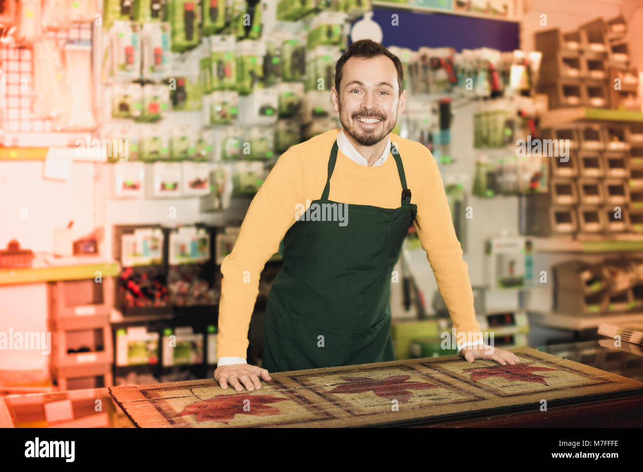 Handsome male seller displaying various items in garden equipment shop ...