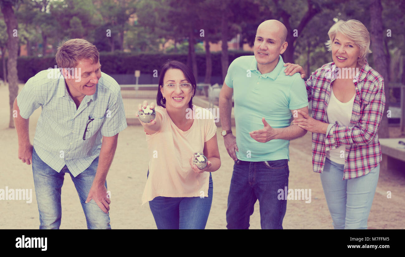 Cheerful males and females playing petanque in th park on holidays ...