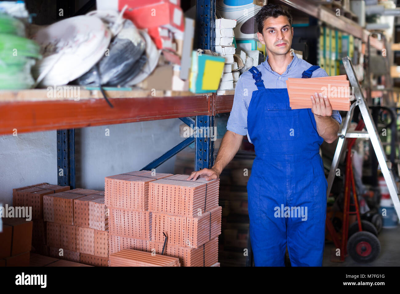 Shop assistant is checking quality of tiles in the building store Stock ...