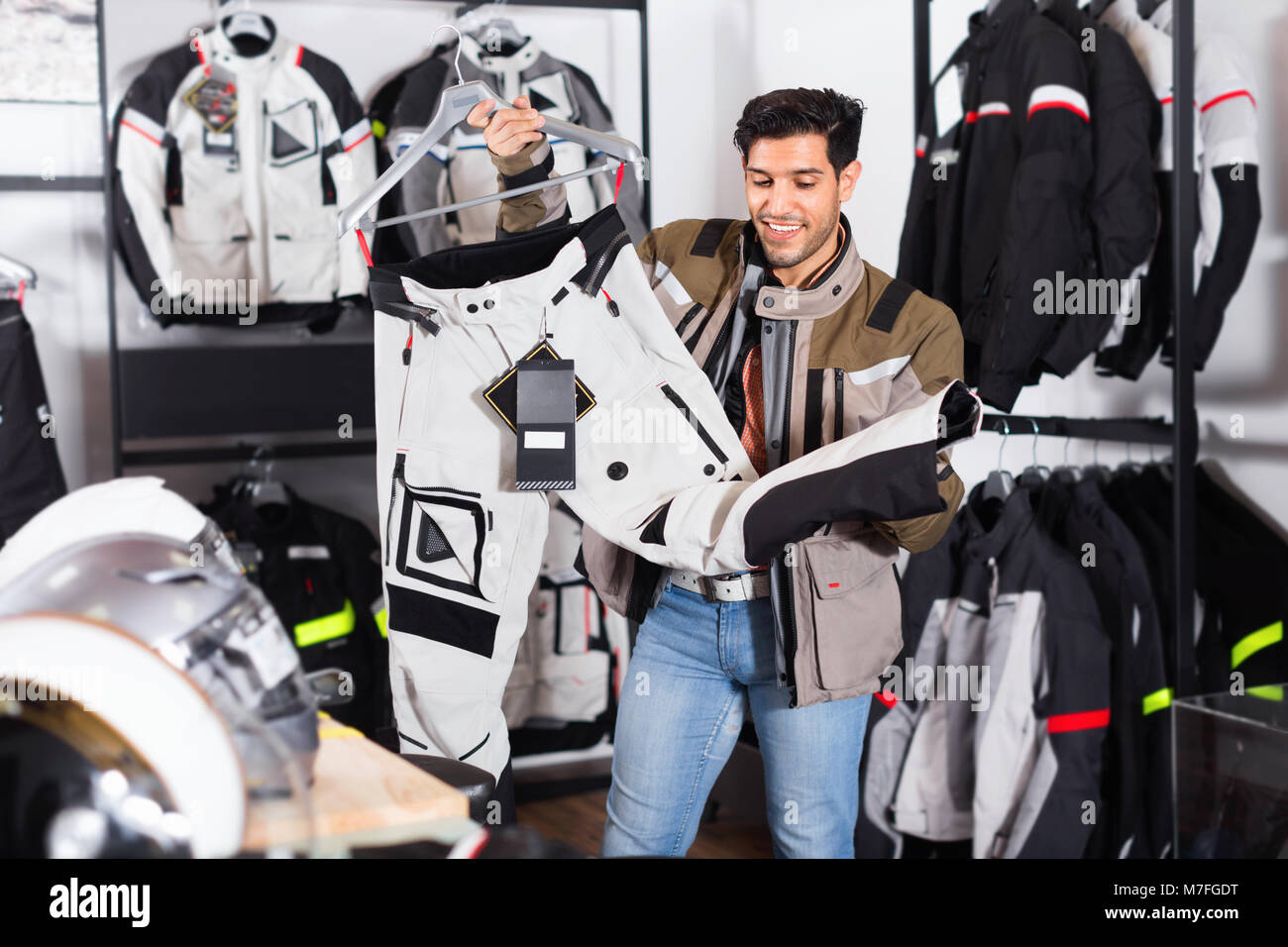 Happy cheerful smiling male customer is choosing modern trousers in the ...