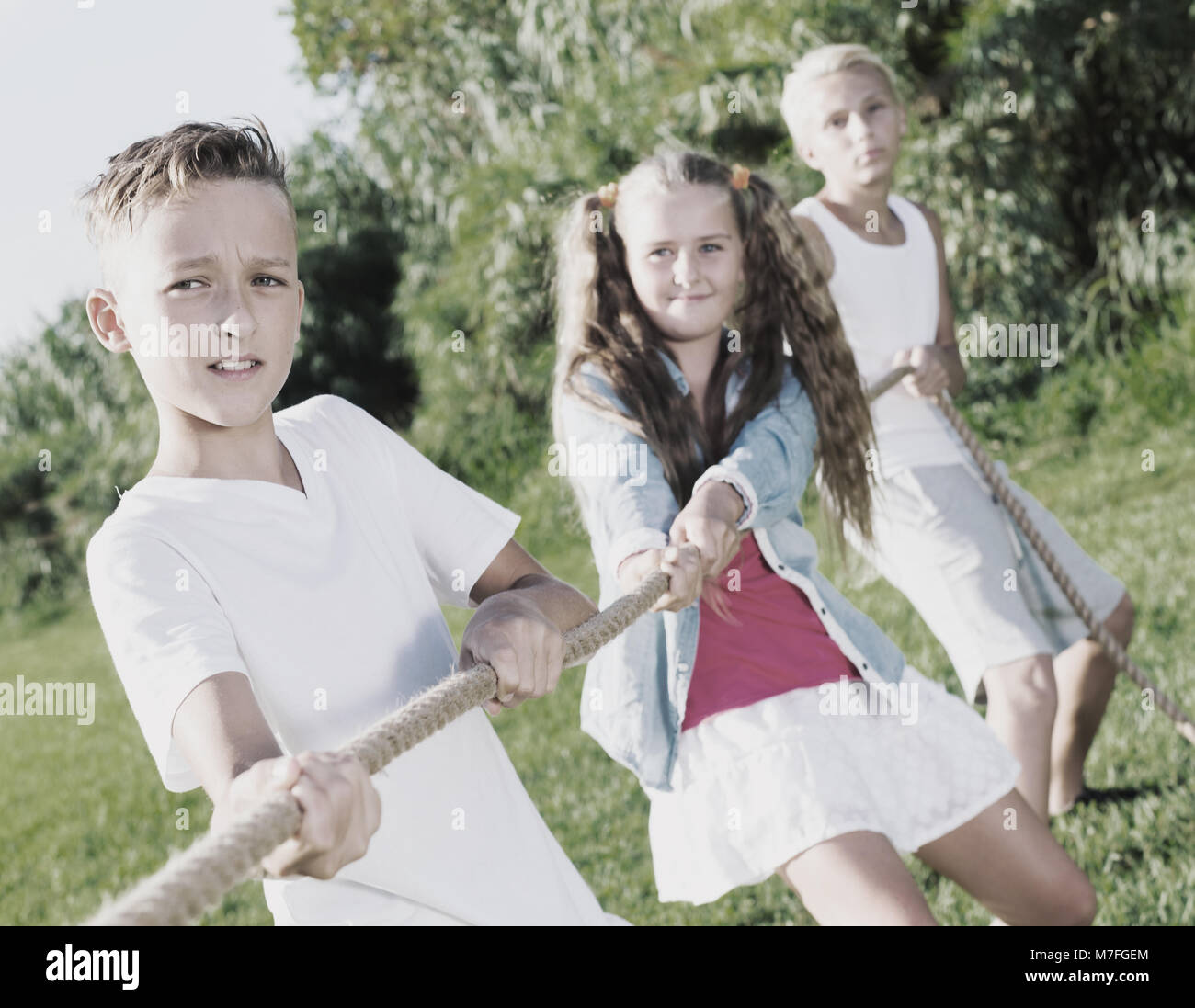Children playing tug of war during joint games outdoors on sunny day ...