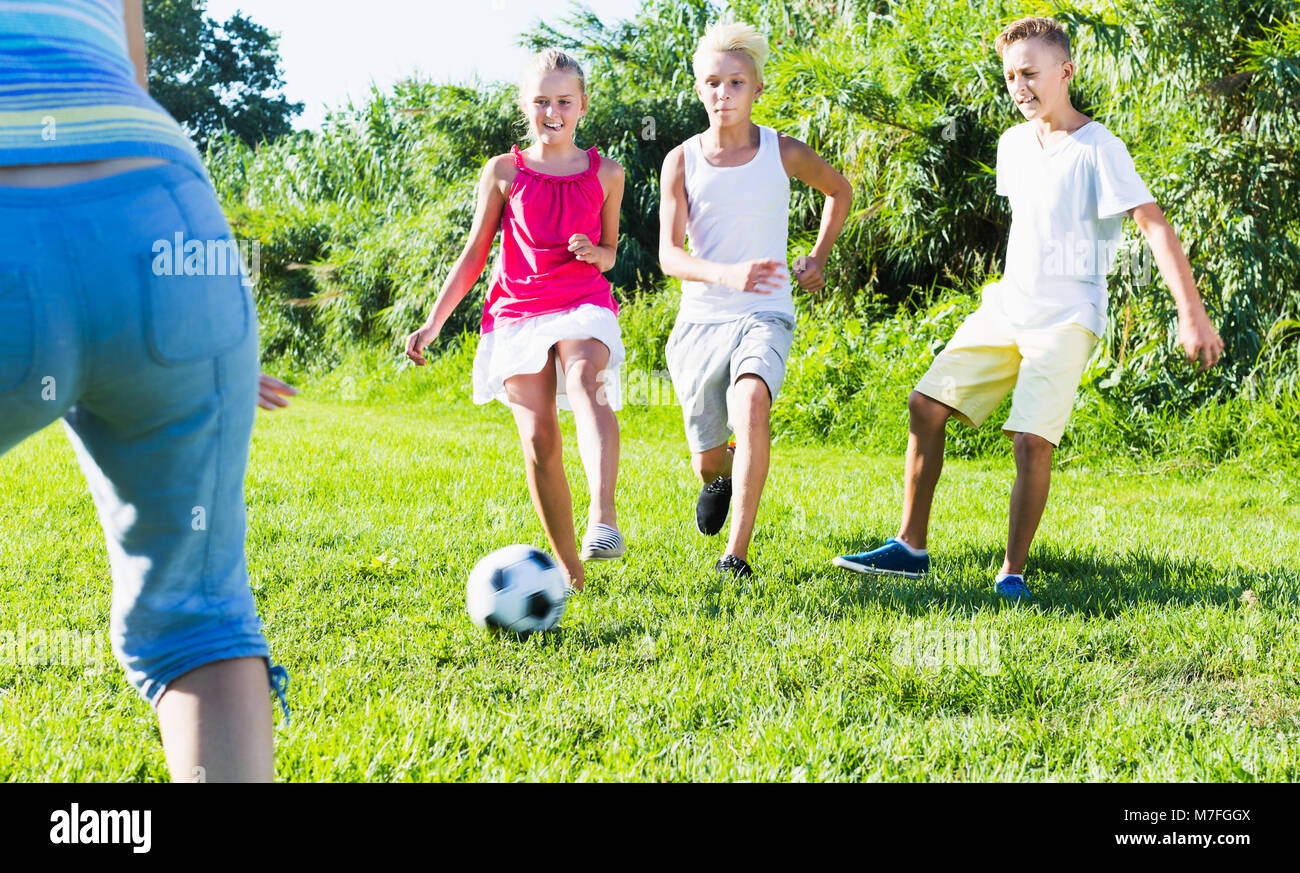 Group of happy children having fun together outdoors playing football ...