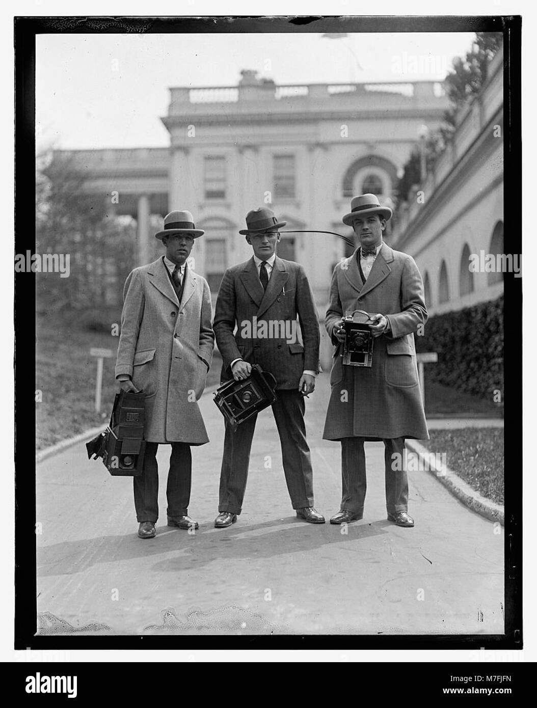 The image captures three men holding cameras outside the White House ...