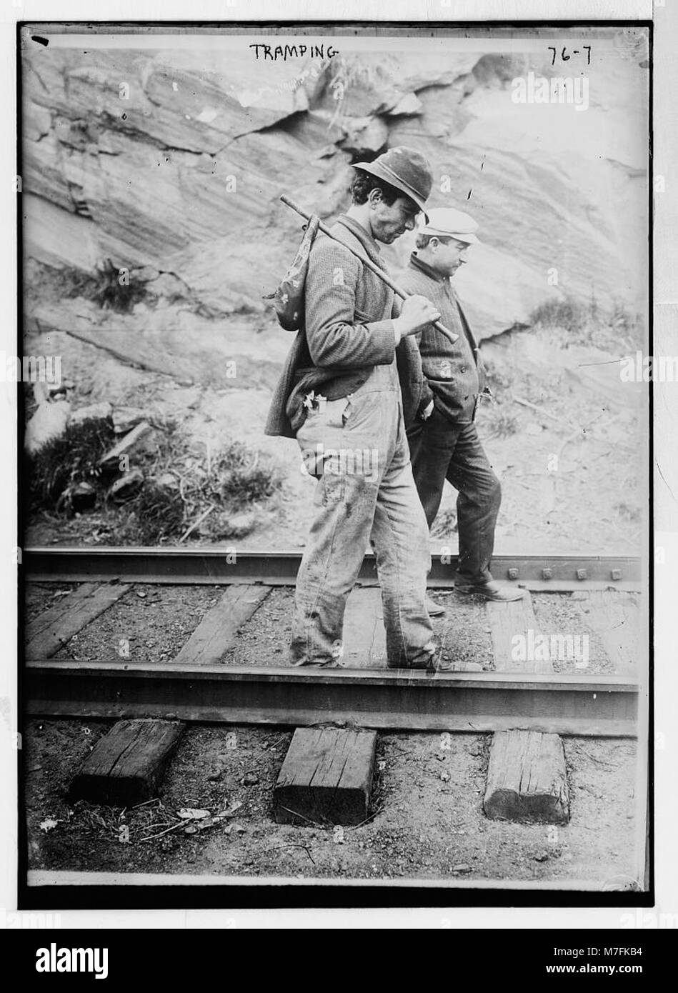 A group of tramps walking along train tracks, an image reflecting the ...