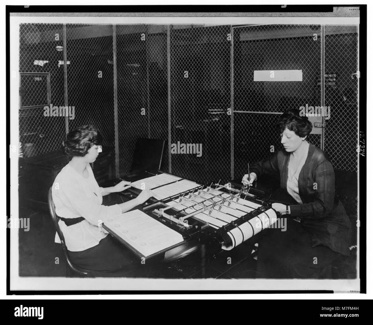 Two women using check signing machine which signs checks issued by the ...