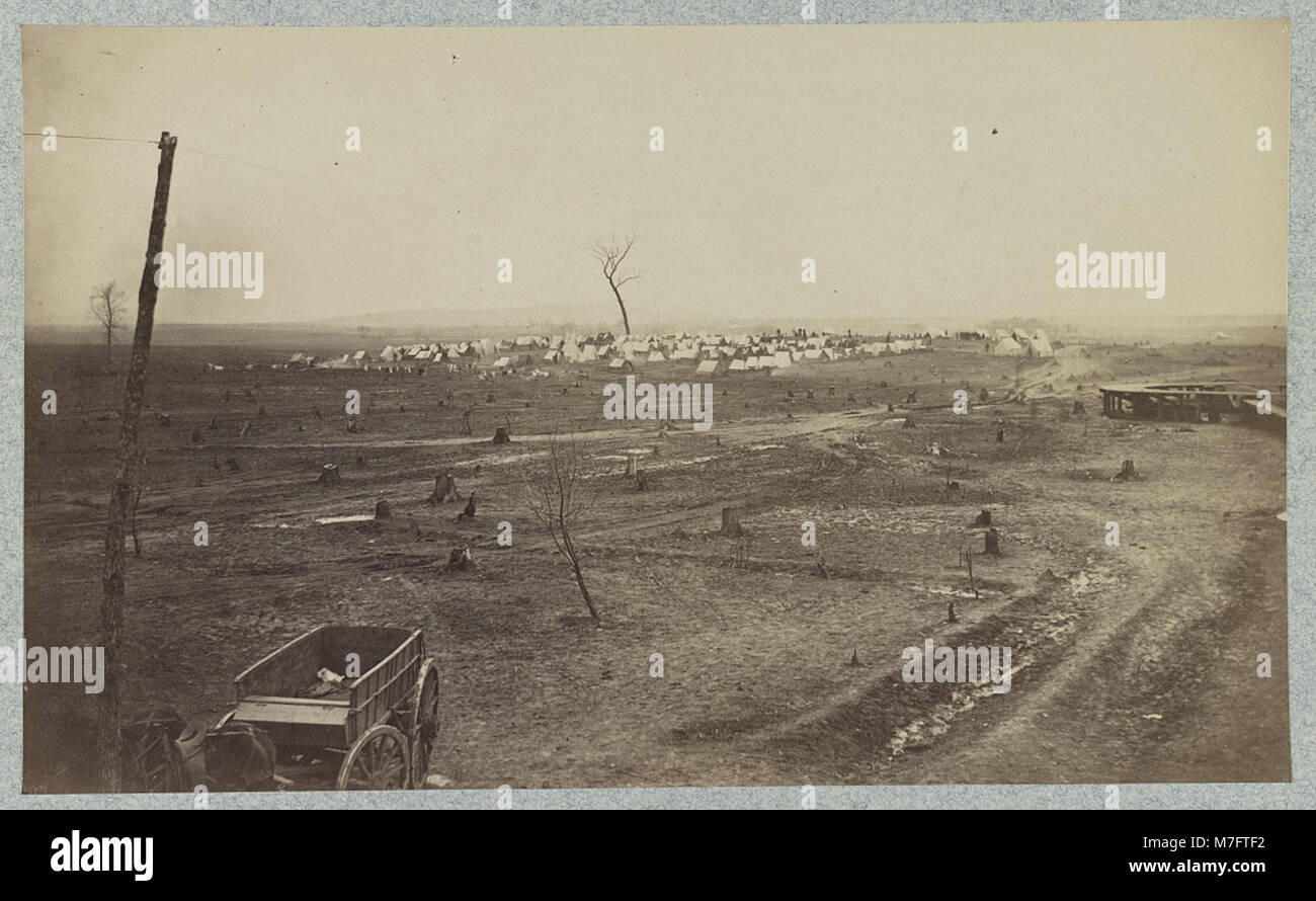 A wagon is parked near a telegraph pole, with a camp visible in the ...