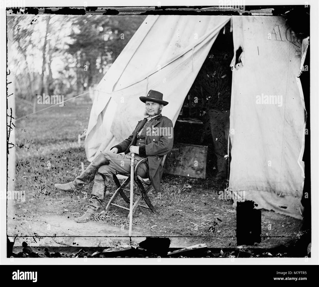 A historical photograph of General Judson Kilpatrick seated by a tent ...