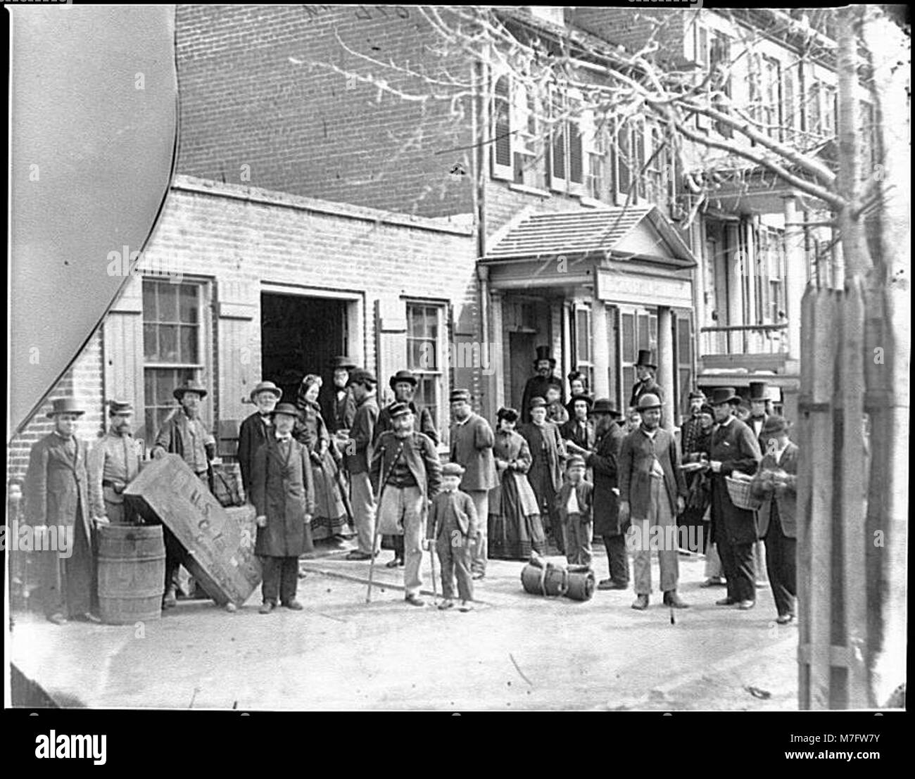 The image shows maimed soldiers and others gathered before the office ...