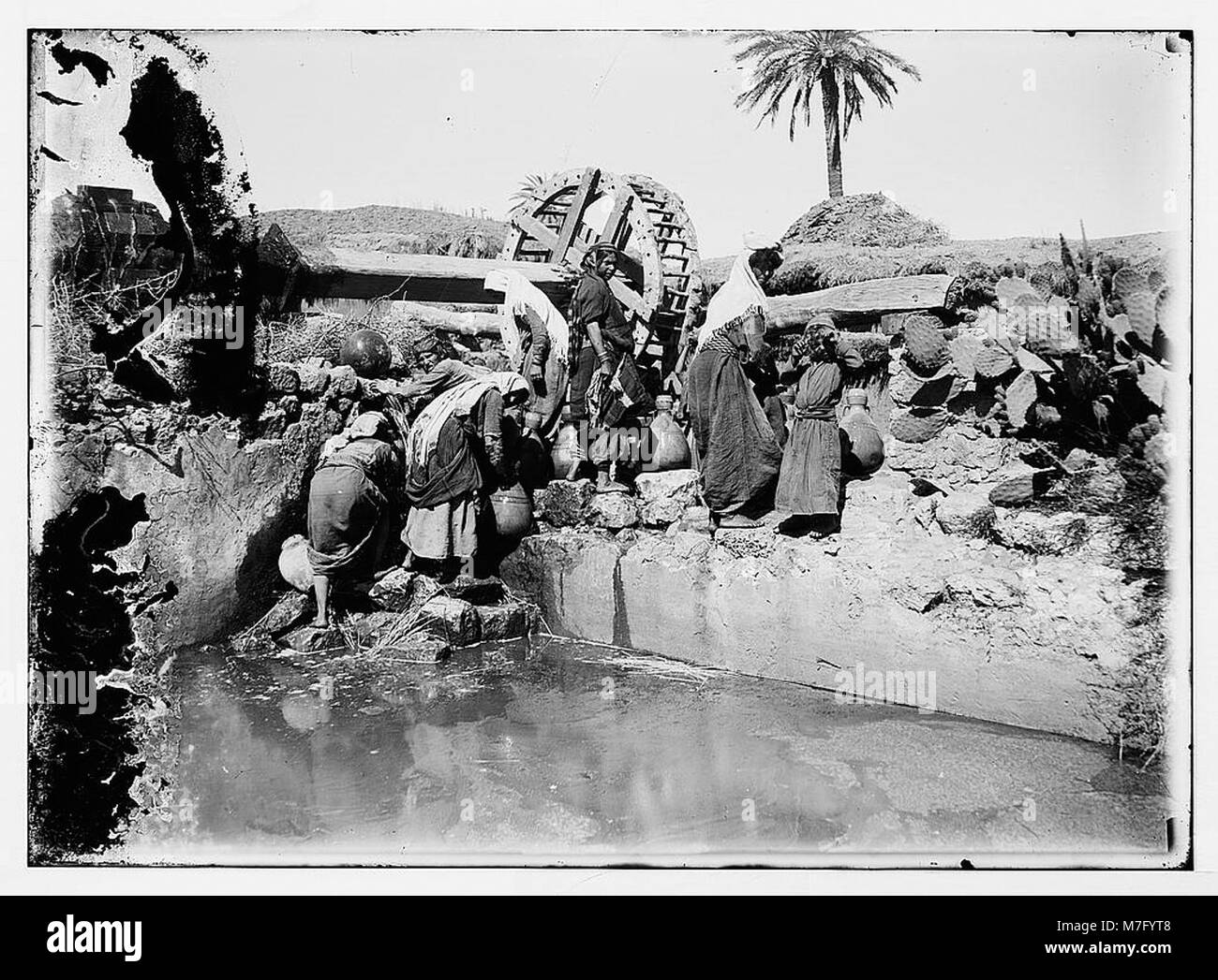 A historical image showing women and children collecting water from a ...