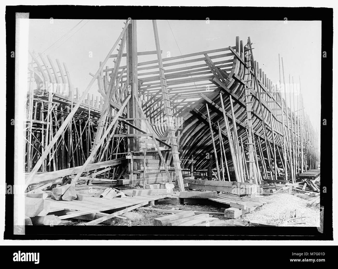 A historical photograph showing the construction of a wooden ship. This ...