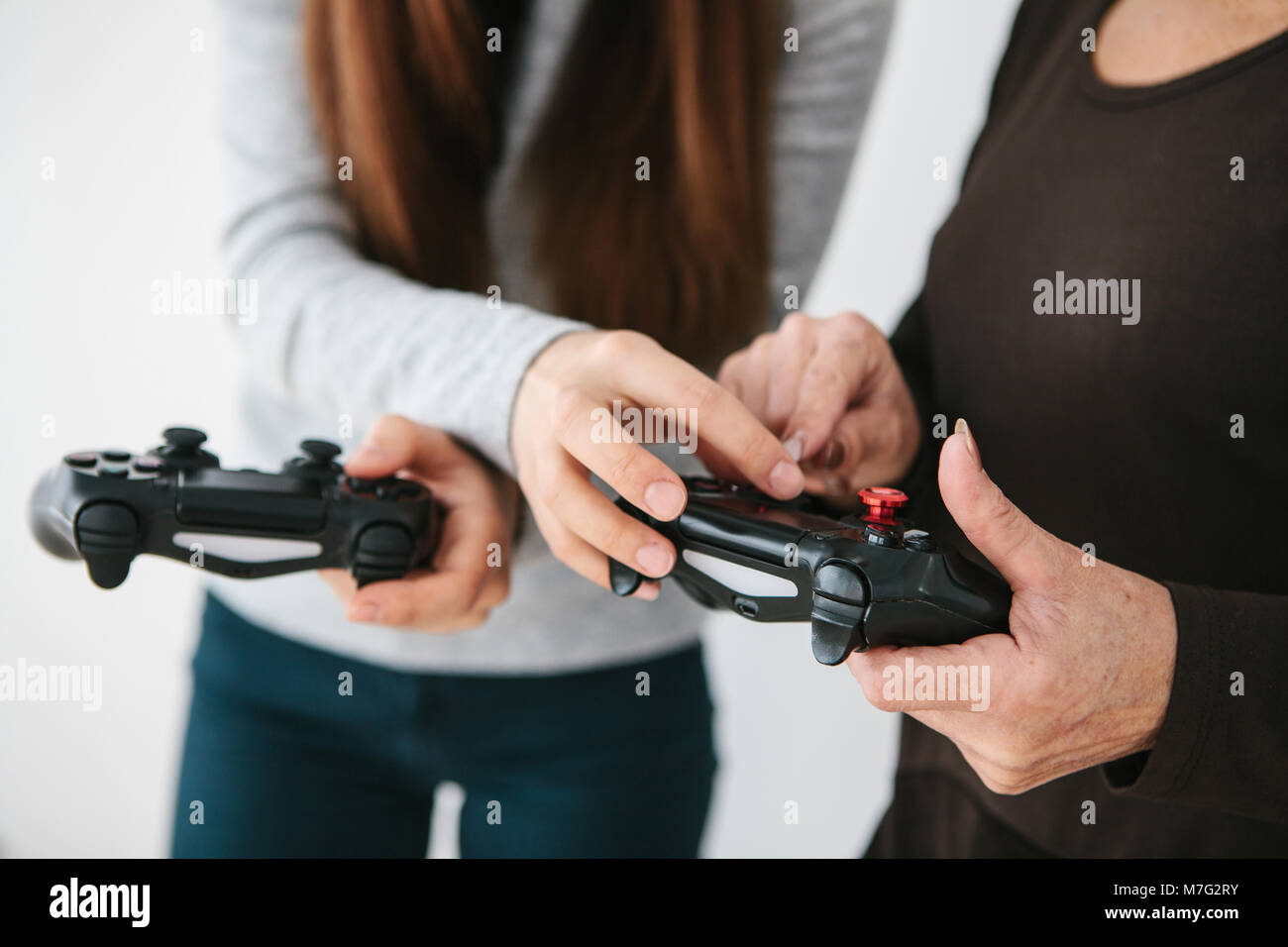 A young girl explains to an elderly woman how to use the joystick for ...