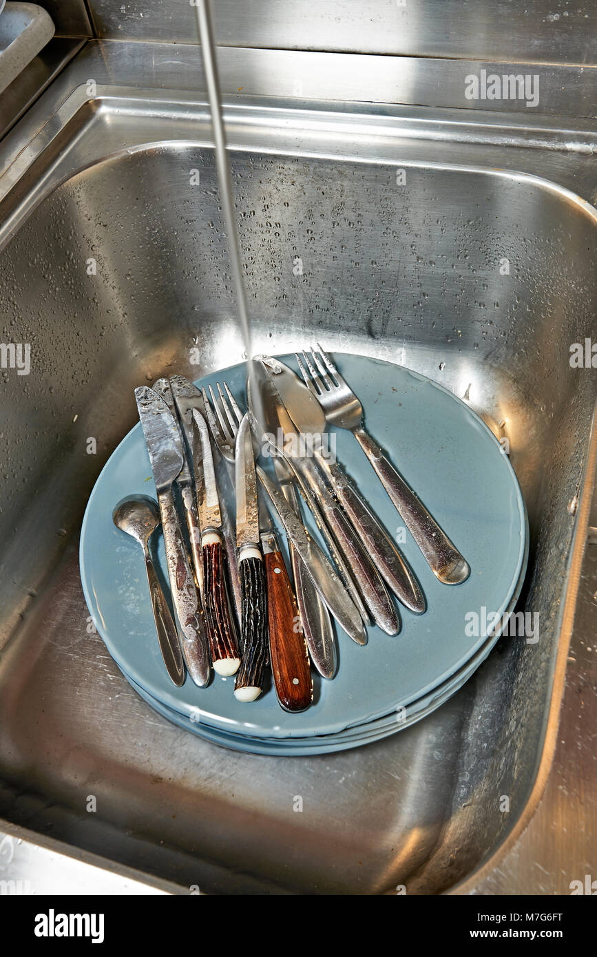 Dirty plates and cutlery in kitchen sink before washing Stock Photo - Alamy
