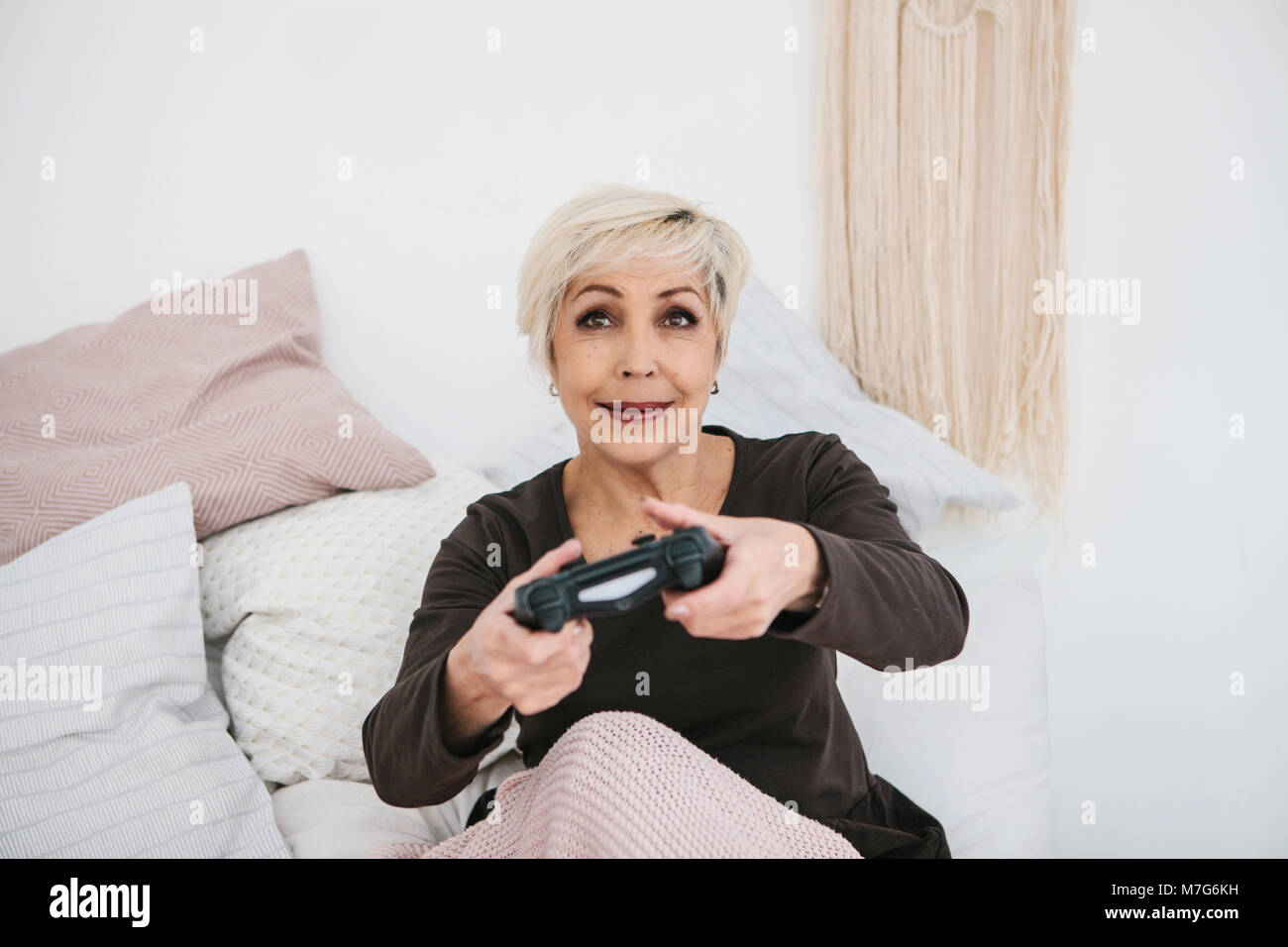 An elderly woman is playing a video game. Elderly person and modern ...