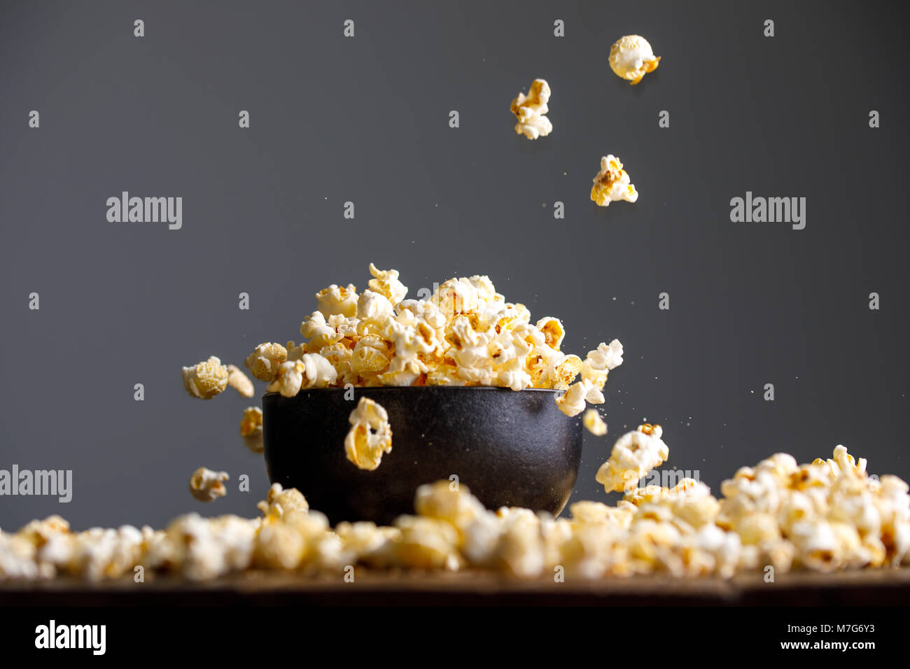 Levitating falling popcorn in a ceramic bowl and around it. Side view ...
