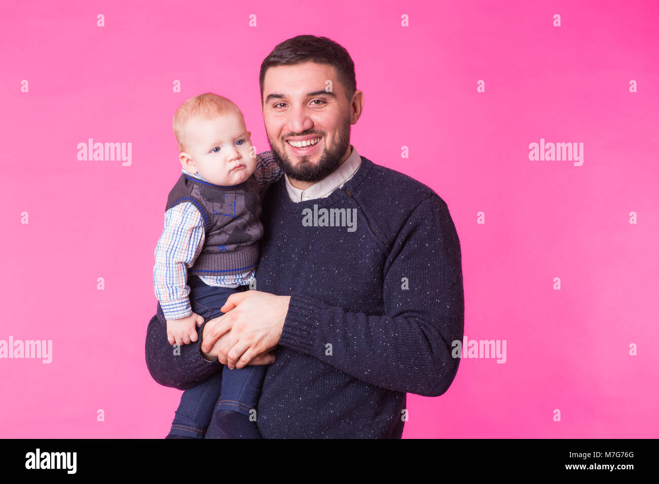 Happy father holding baby son in hands over pink background Stock Photo ...