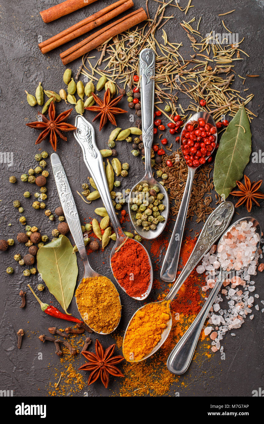 Variety of natural spices, seasonings and herbs in spoons on the stone ...