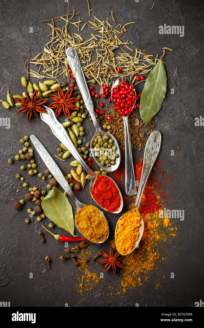 Variety of natural spices, seasonings and herbs in spoons on the stone ...