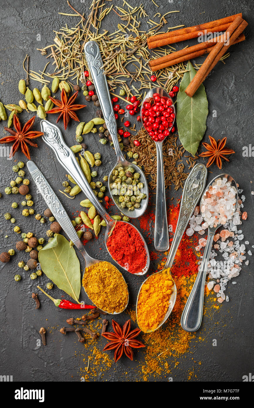 Variety of natural spices, seasonings and herbs in spoons on the stone ...