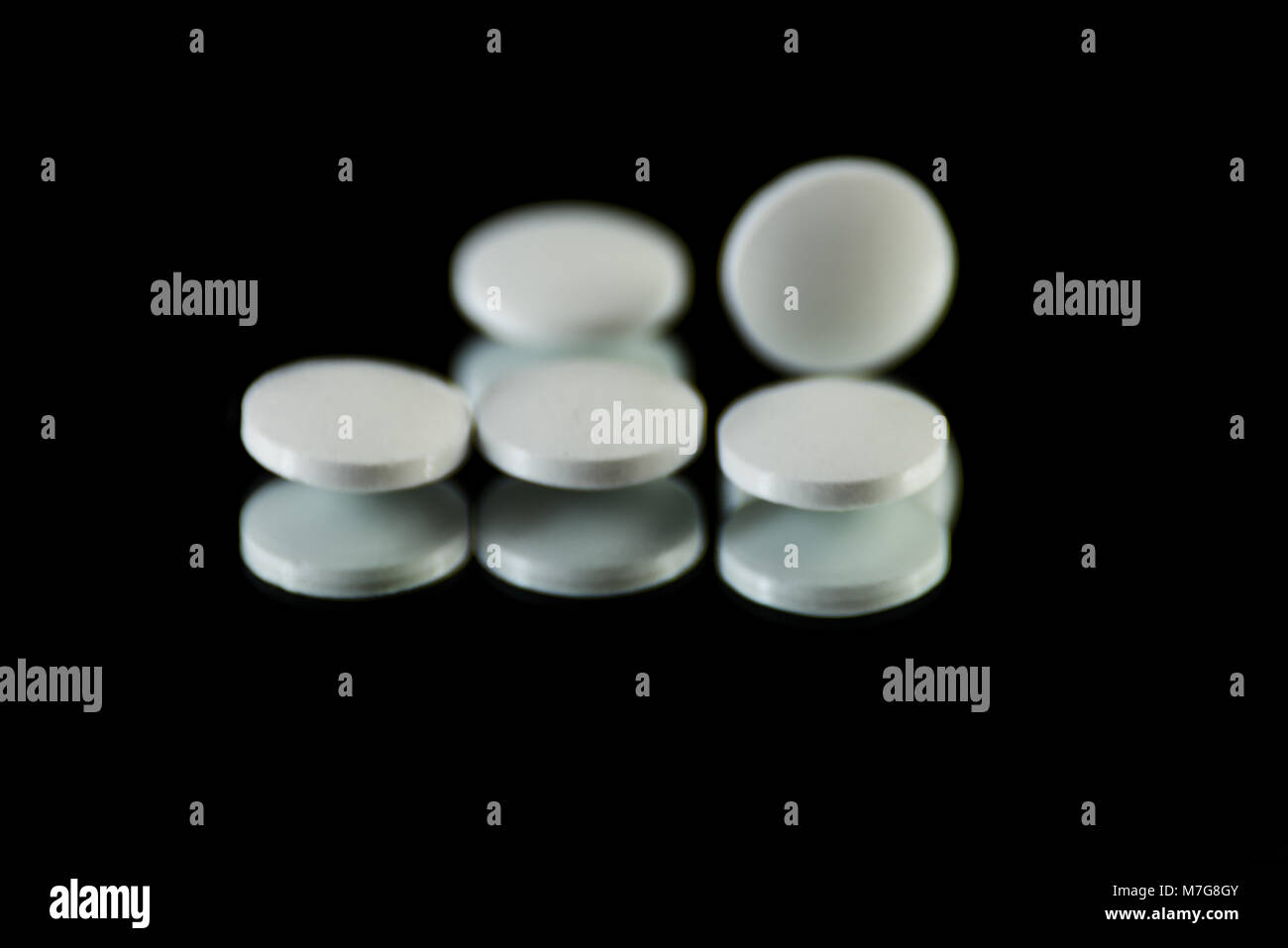 scattered tablets on a black background, pills reflected in the mirror ...
