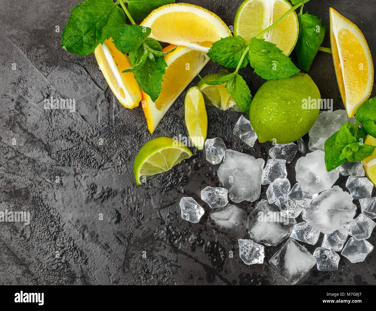 Lime, lemon, mint and crushed ice on a black background. The ...