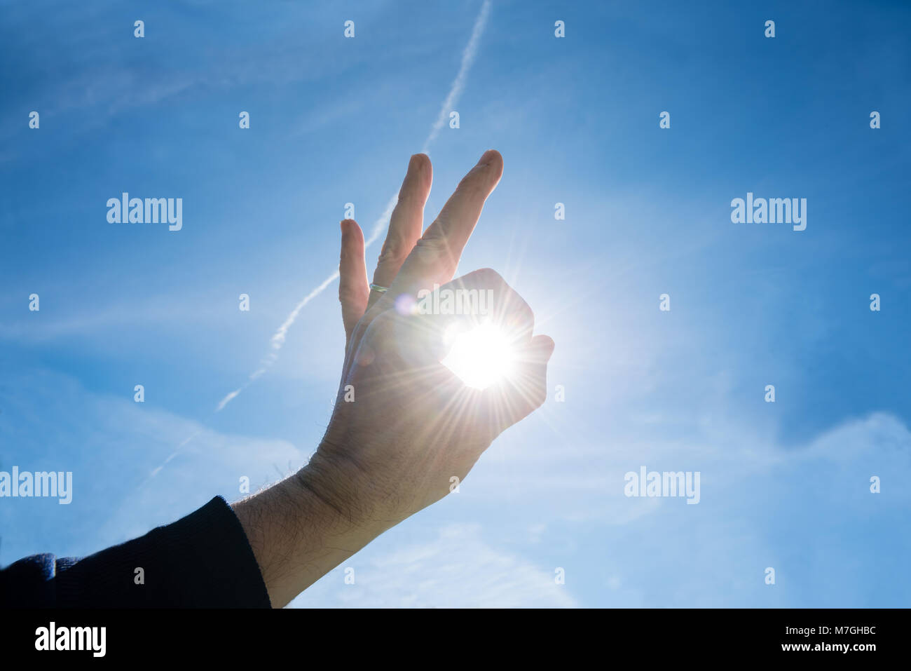 hand making OK gesture surrounding the sun causing camera flare Stock ...