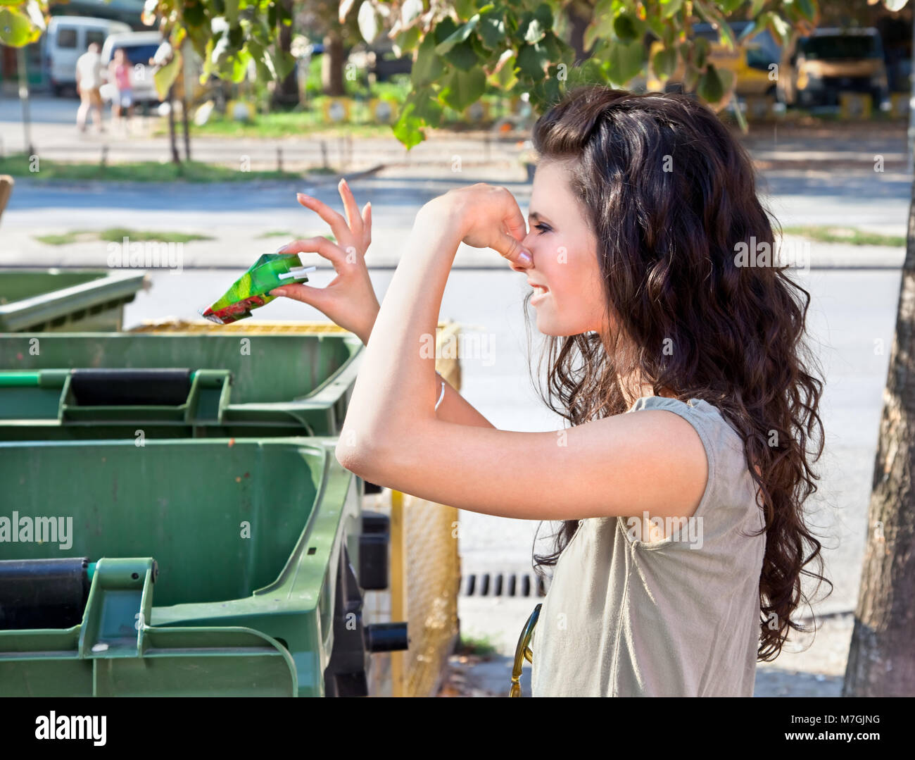 Woman throws garbage in a green plastic dumpster Stock Photo - Alamy