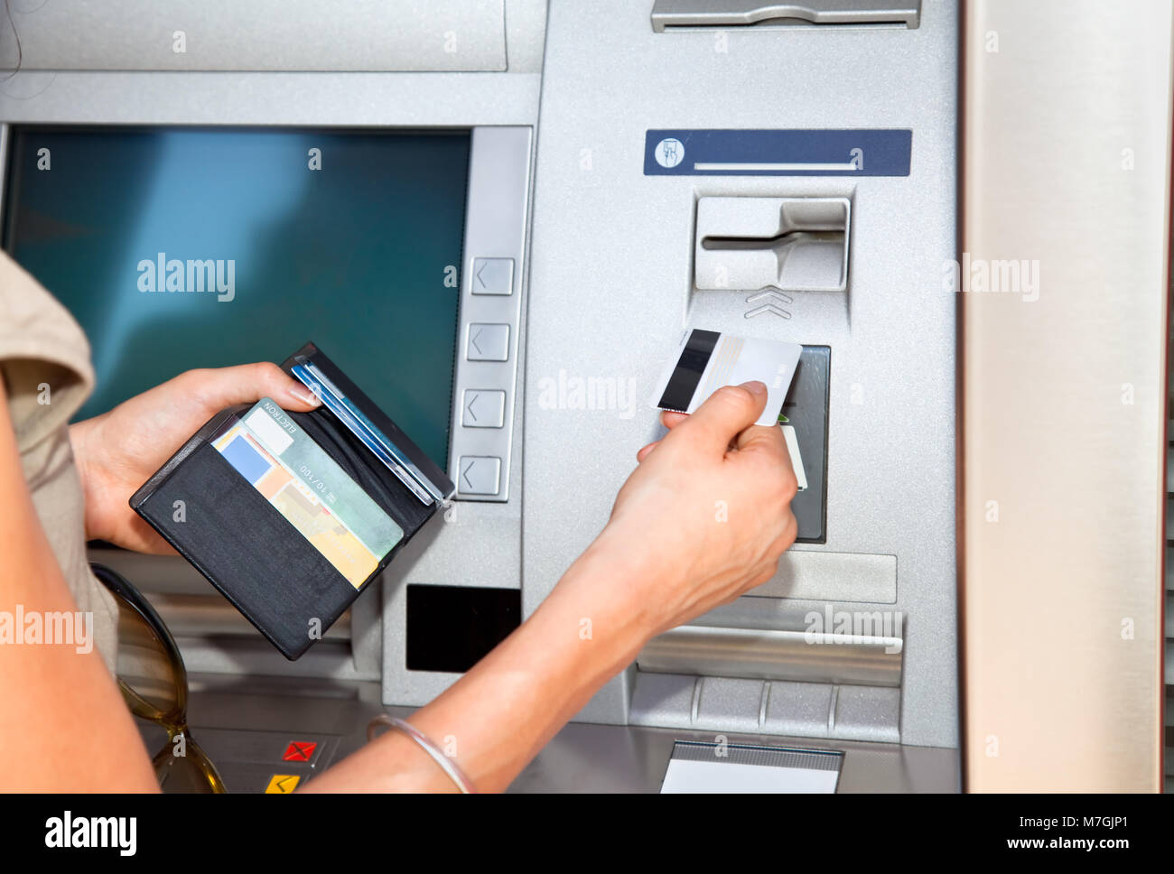 Cash withdrawal. Woman's hand inserting plastic card Visa into the ATM ...