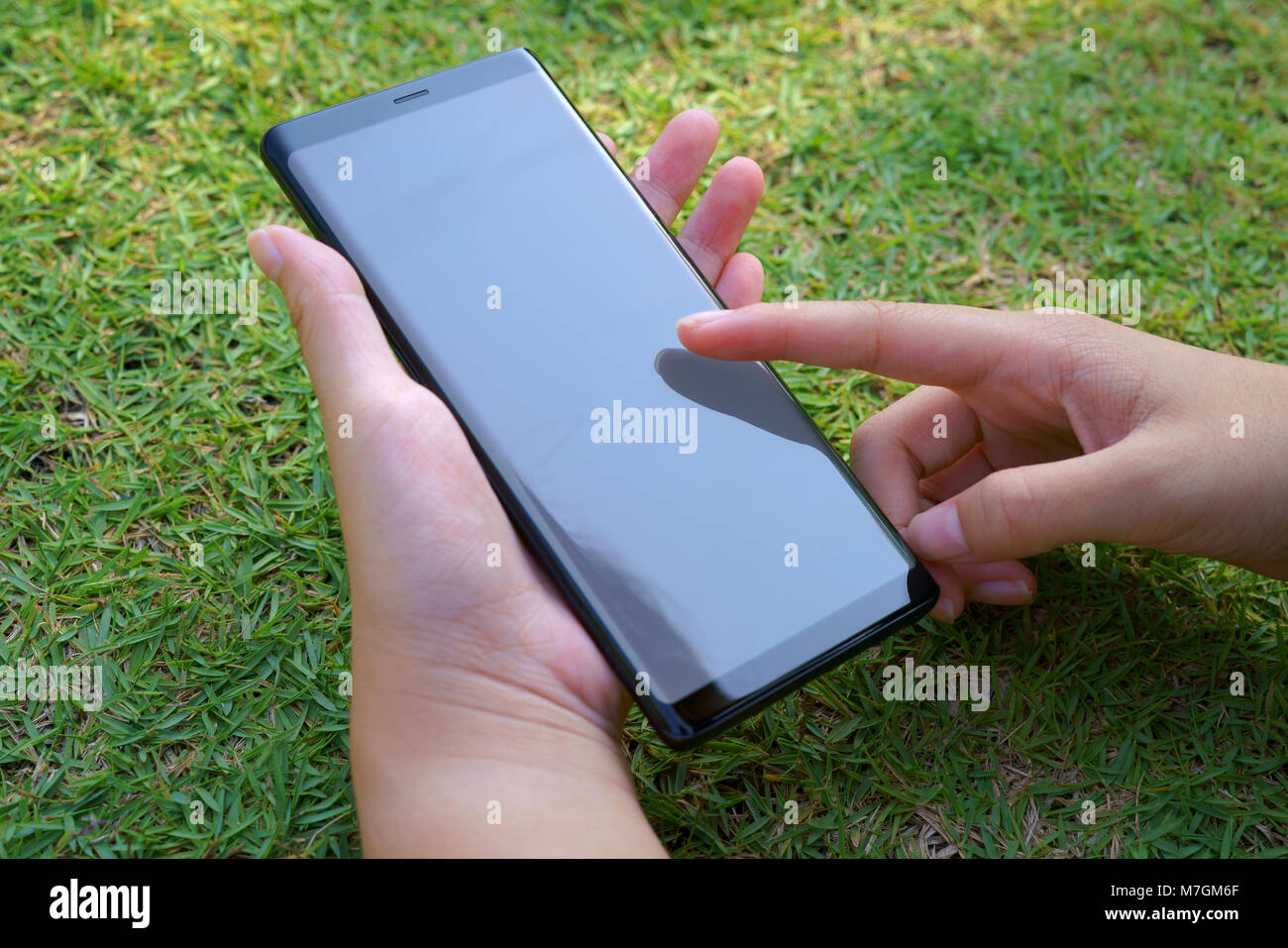Female hand holding the smartphone Black and Green nature Stock Photo ...