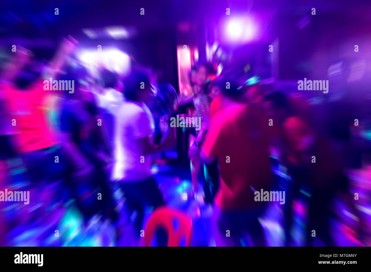 Group of people are dancing under purple light in the club feeling fun ...