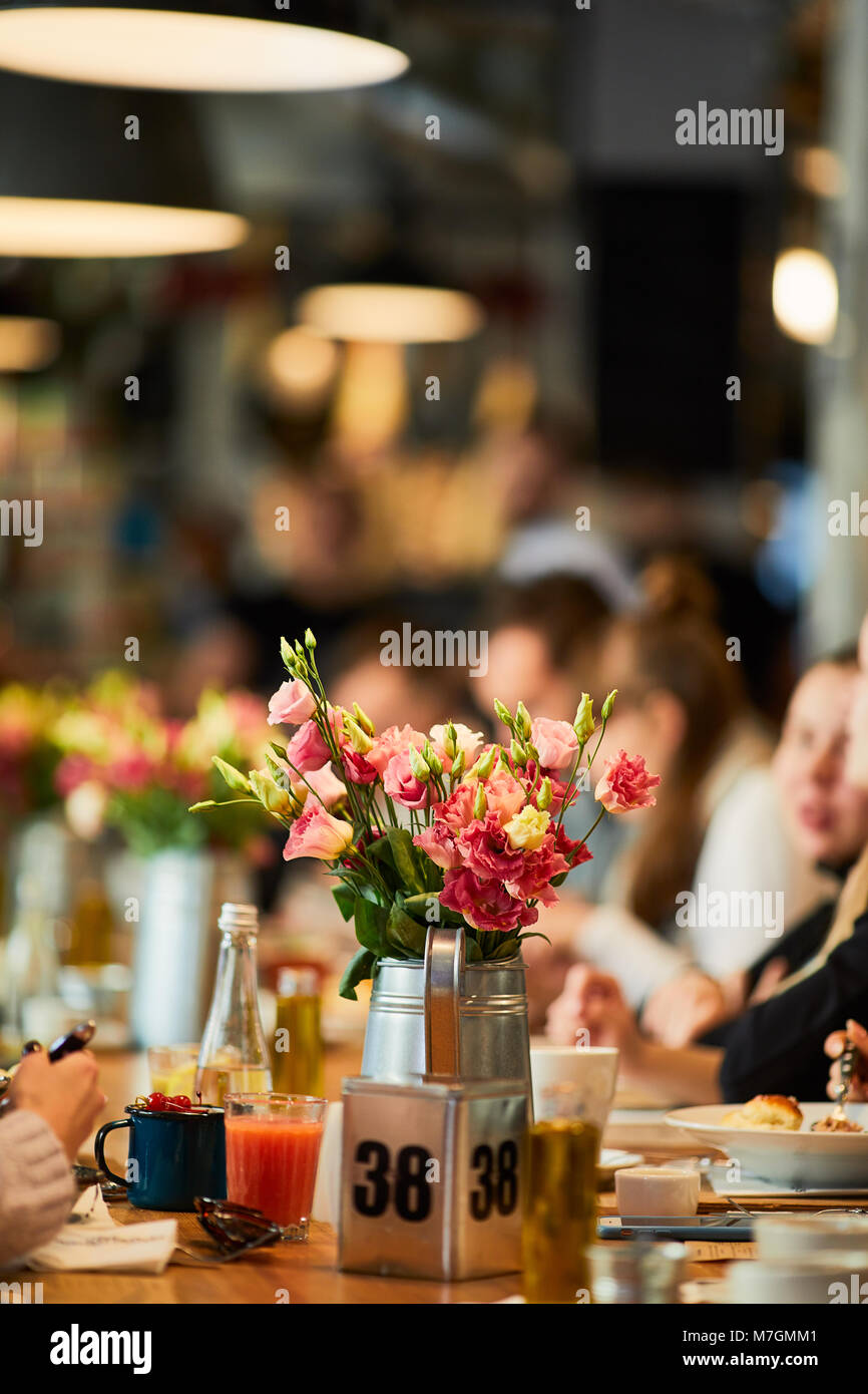 Table with flowers and people setting around Stock Photo - Alamy