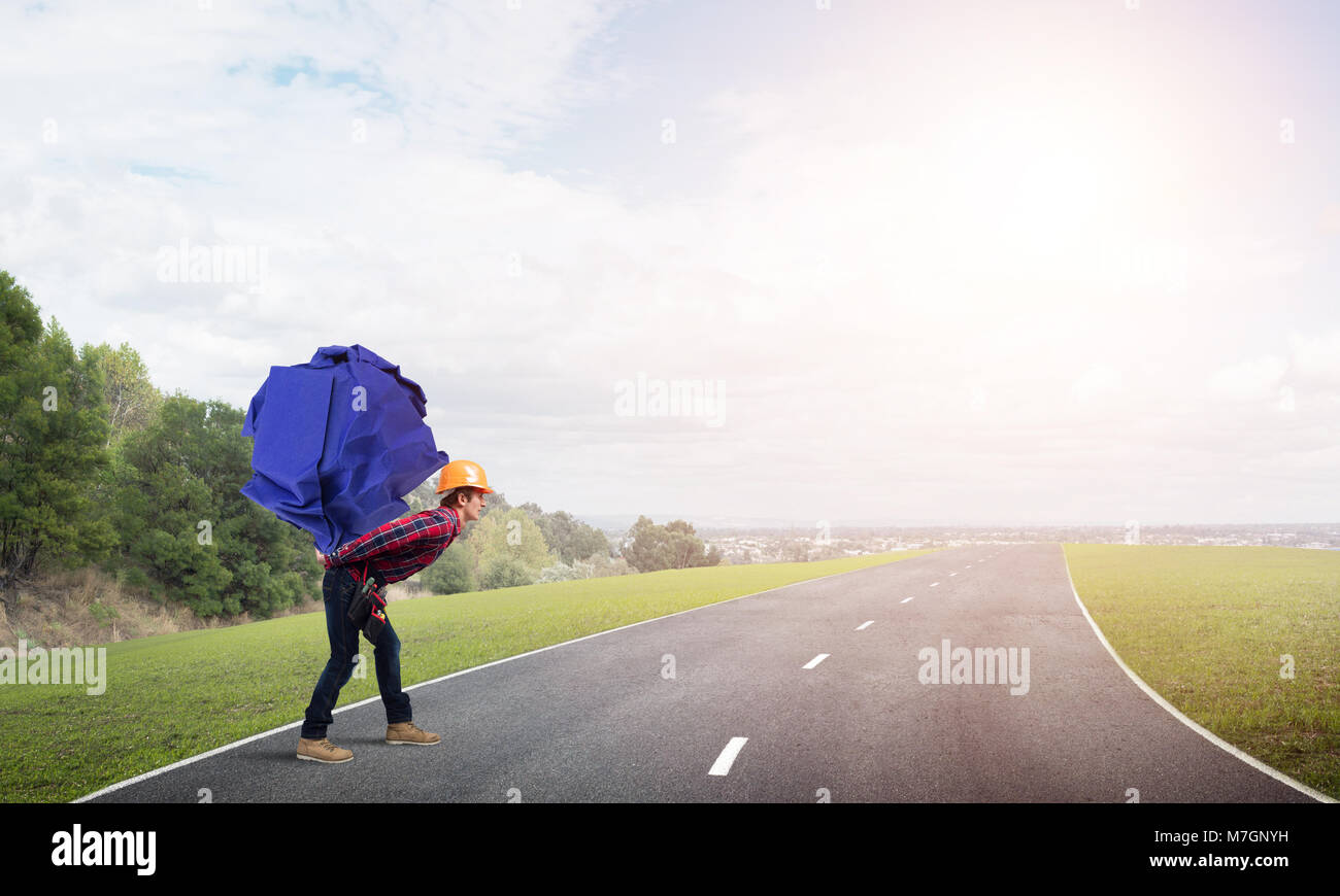 Builder man carrying paper ball on his back Stock Photo - Alamy