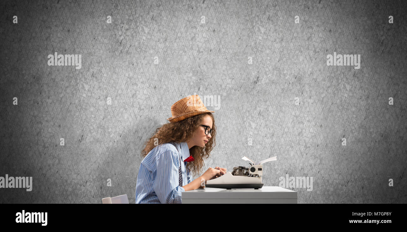 Side view of young beautiful woman writer in hat and eyeglasses using ...