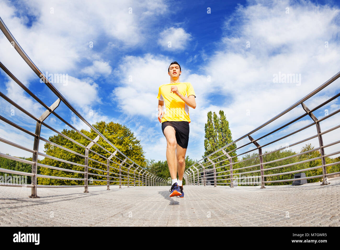 Active man running sprinting across the bridge outdoors in summer Stock ...